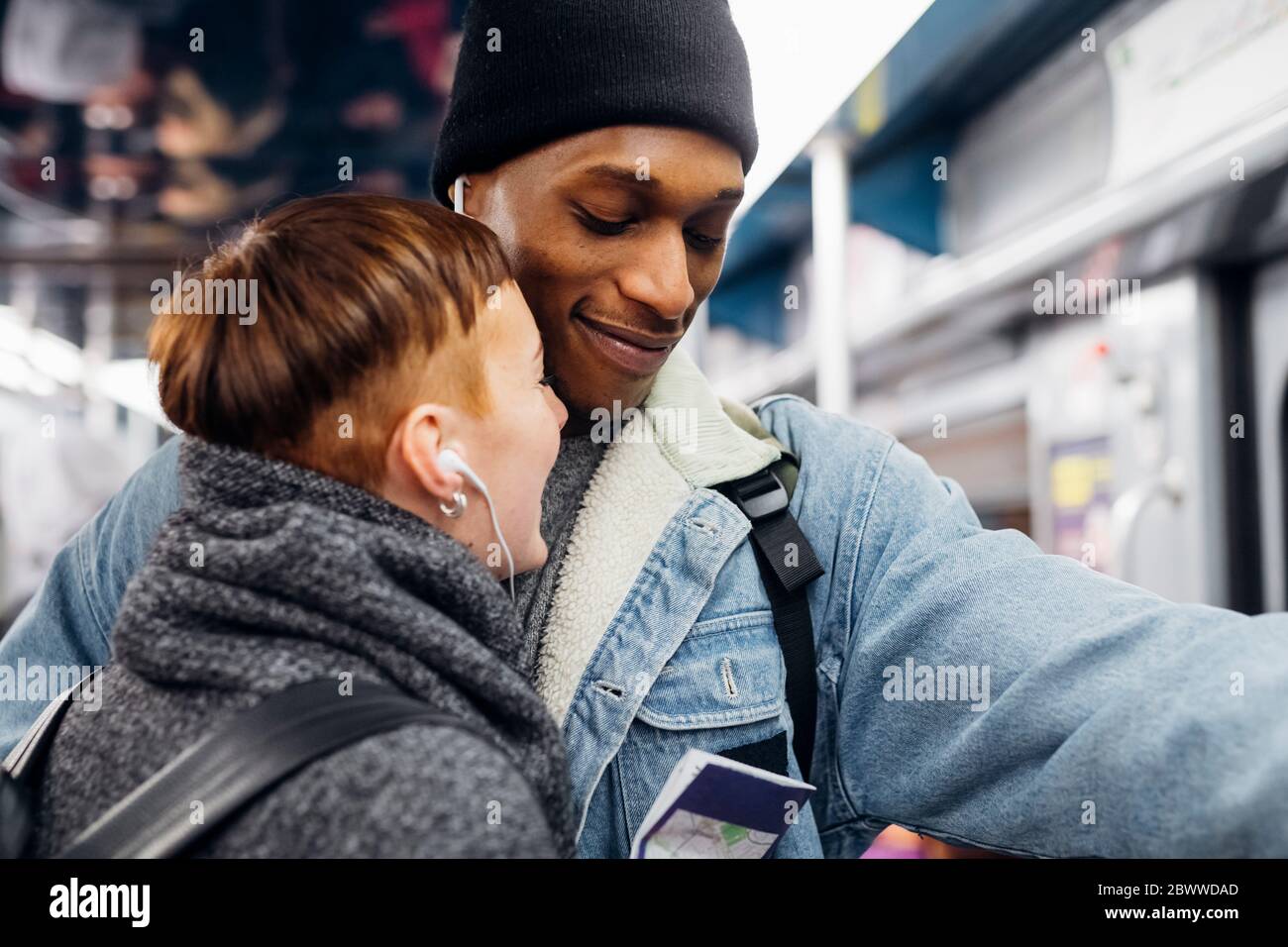 Portrait of young couple sharing earbuds on a subway Stock Photo - Alamy