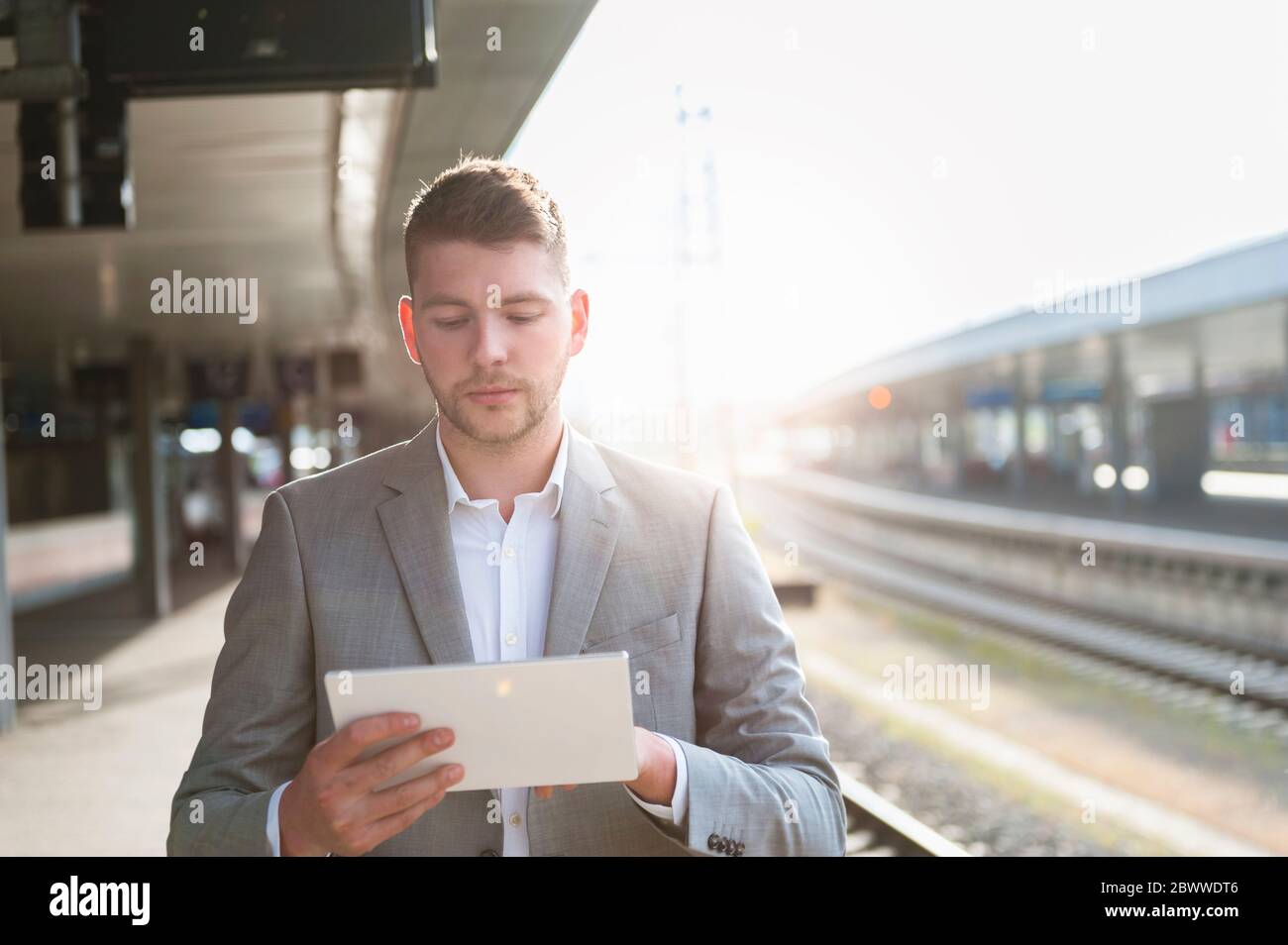Young businessman using tablet at the train station Stock Photo - Alamy