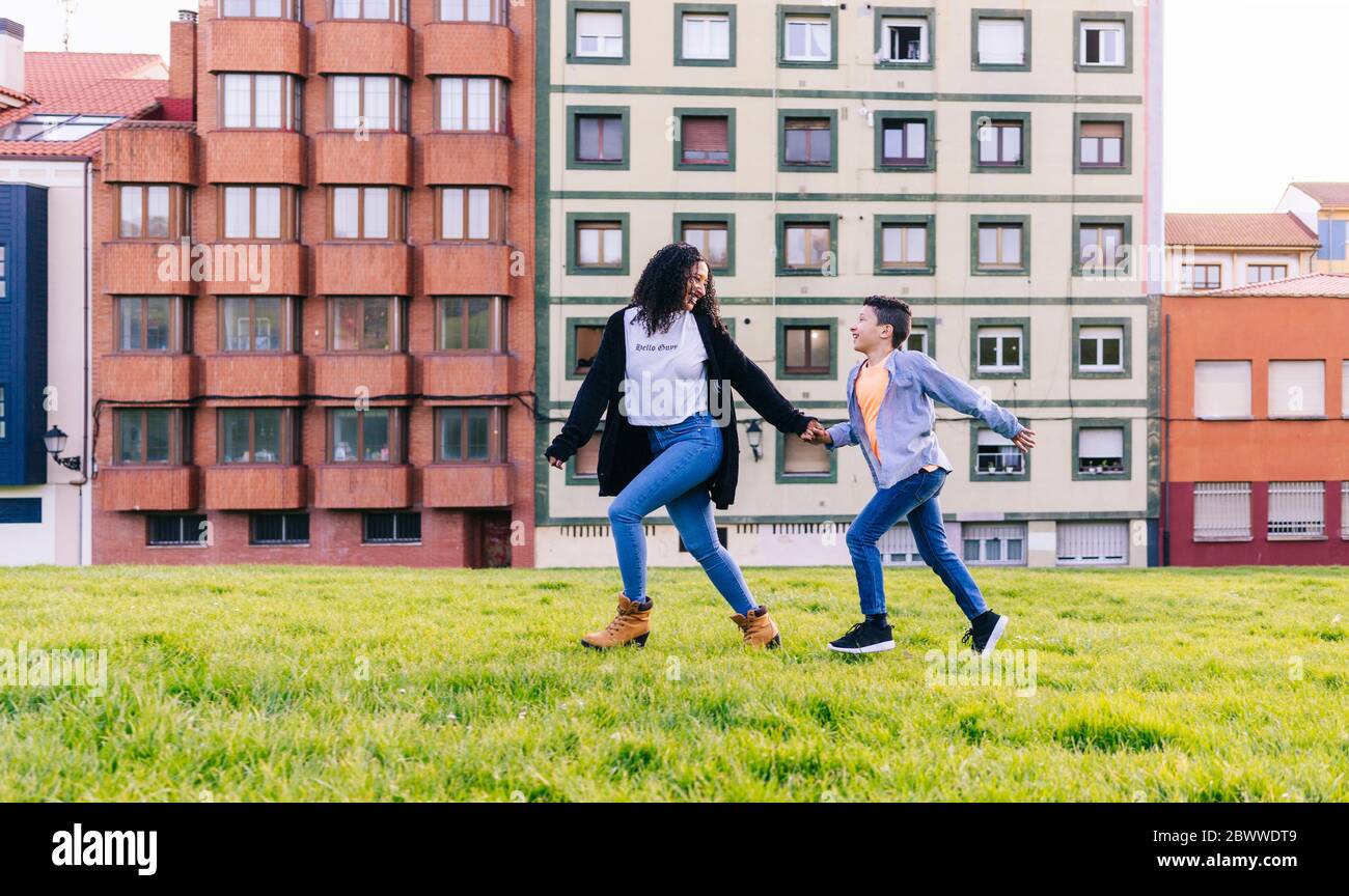 Mother and son running hand in hand on a meadow Stock Photo - Alamy