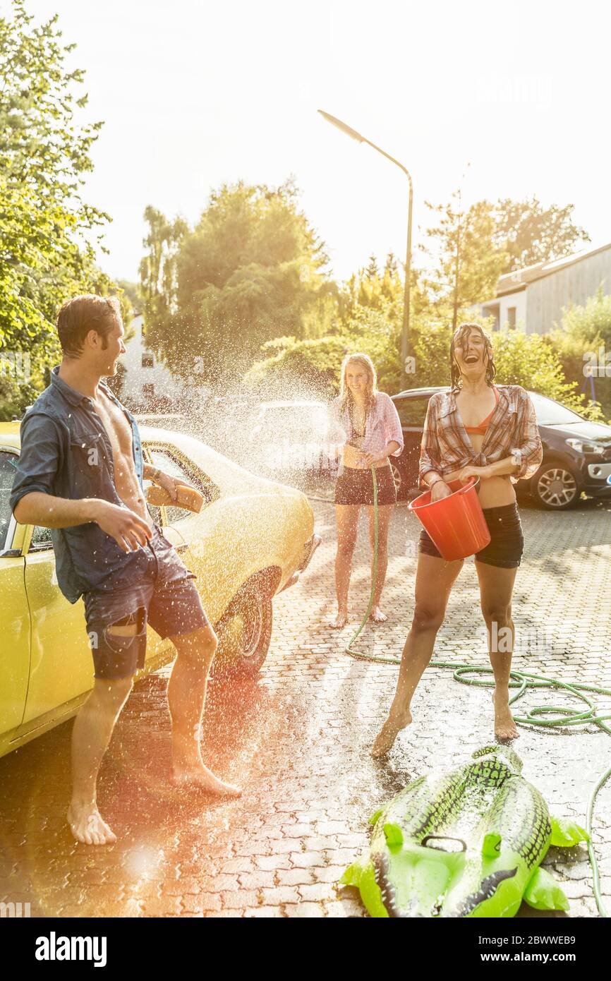 Three friends washing yellow vintage car in summer having fun Stock ...