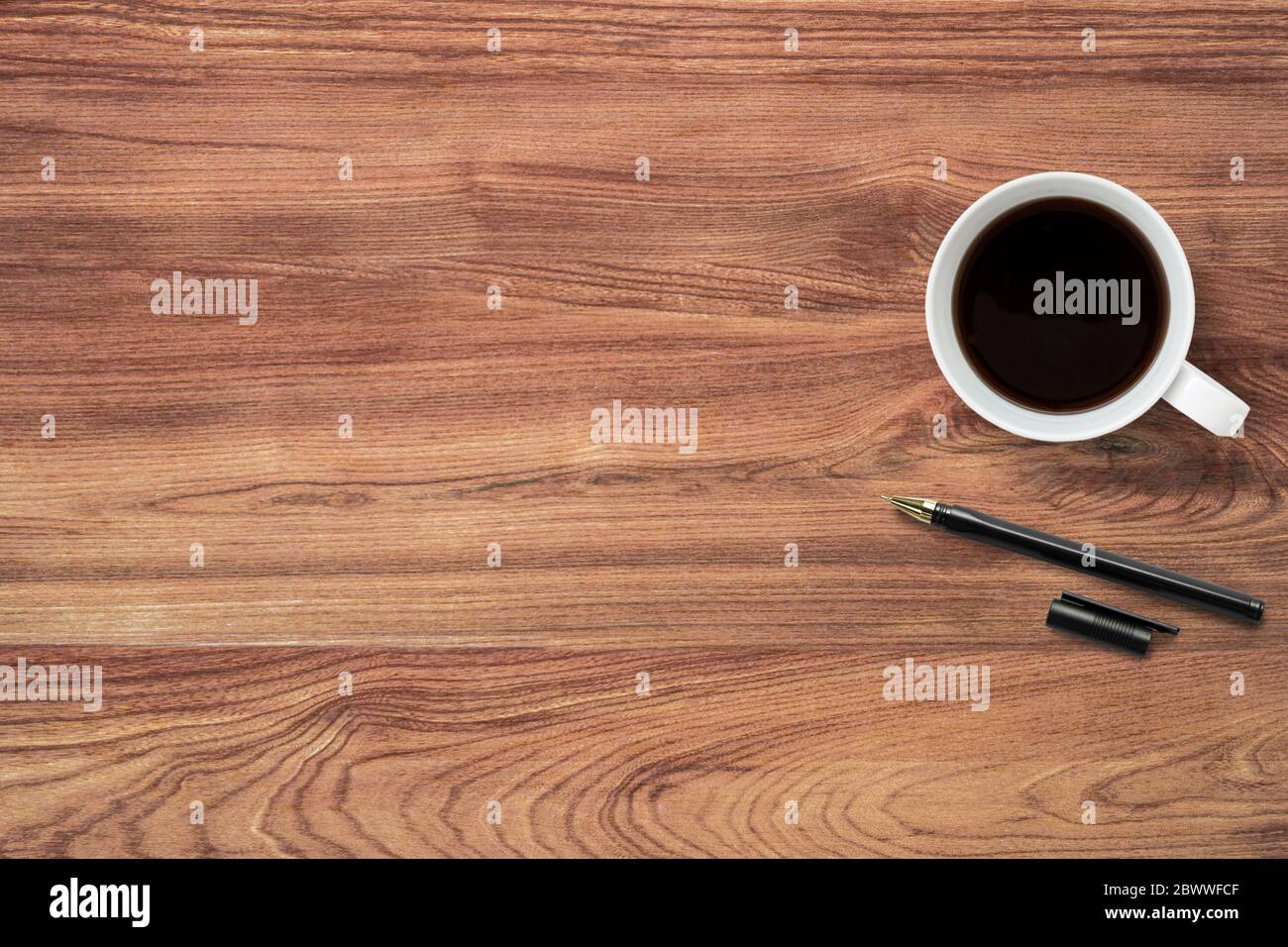 Cup of coffee and pen are on top of wood table. Top view with copy ...
