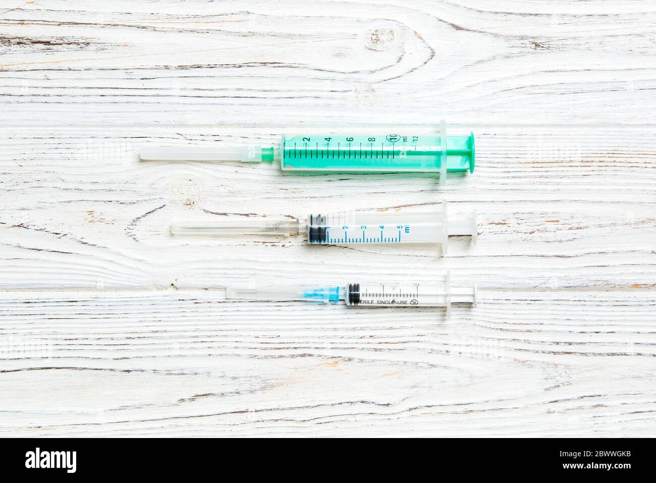 Top view of syringes of different sizes on wooden background. Medical ...