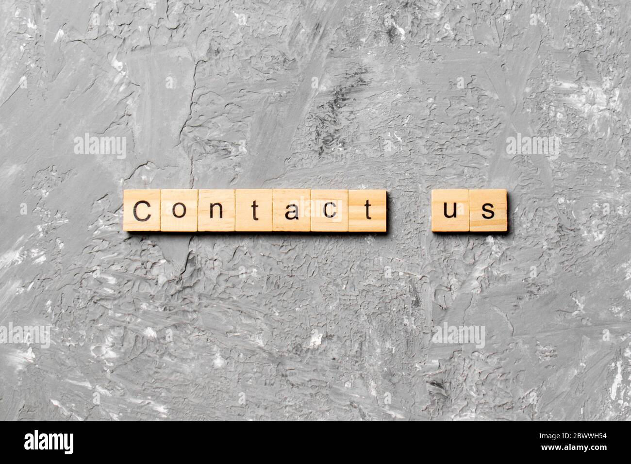 Contact Us word written on wood block. Contact Us text on cement table ...