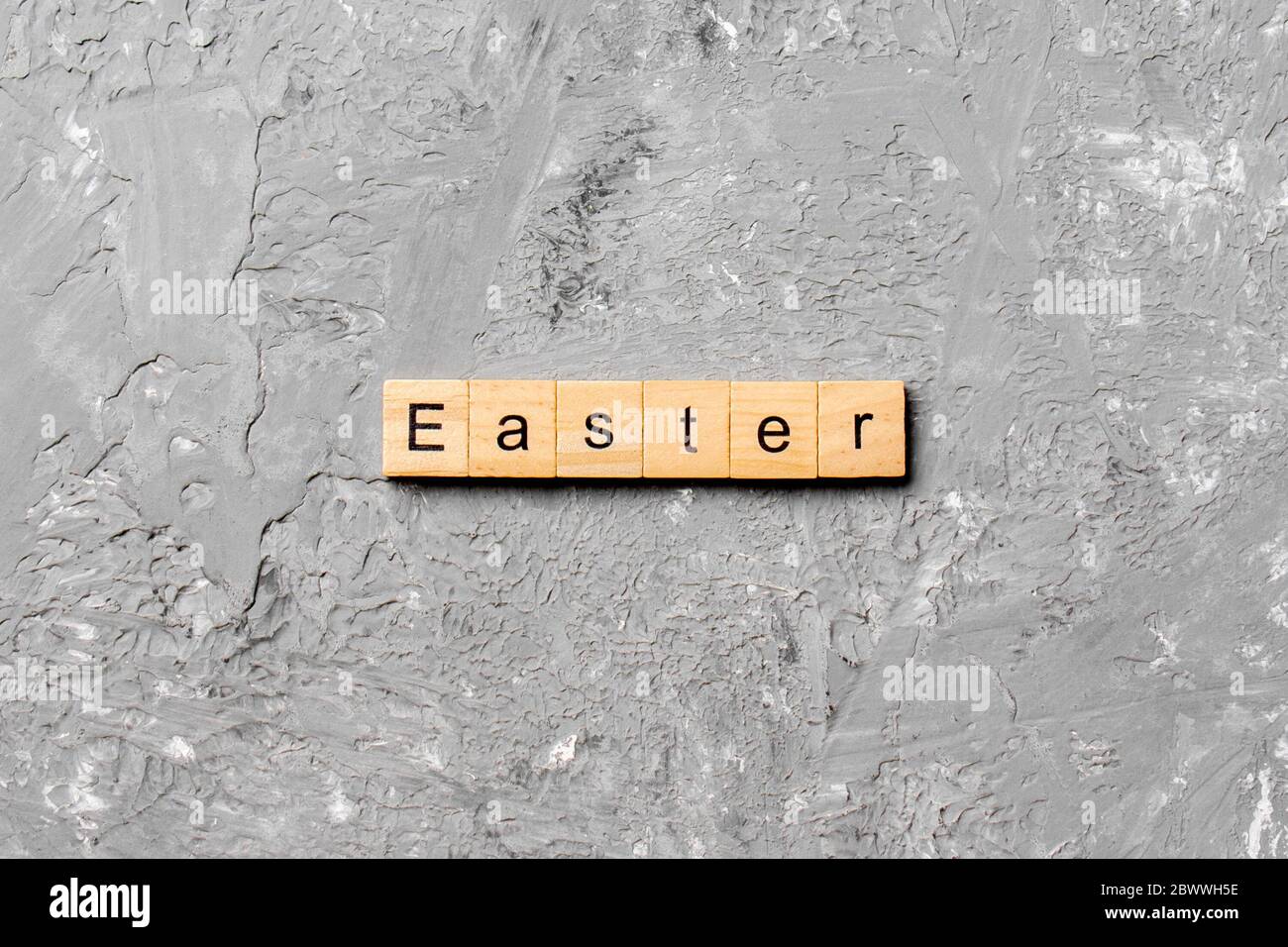 Easter word written on wood block. Easter text on cement table for your ...