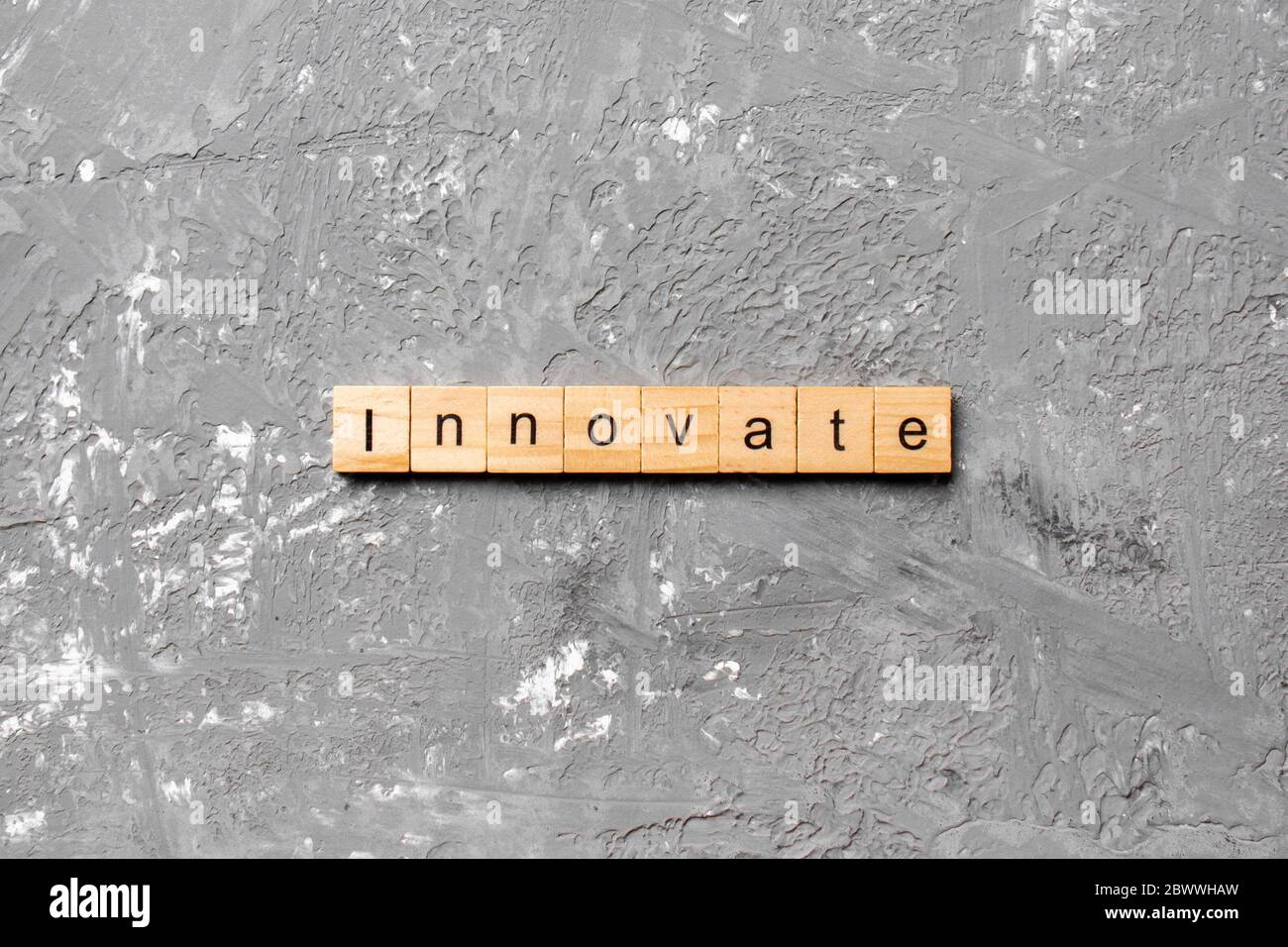 INNOVATE word written on wood block. INNOVATE text on cement table for ...