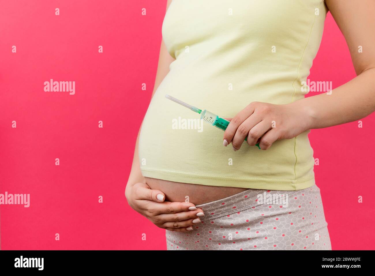 Close up of syringe for injection in pregnant woman's hand at colorful ...