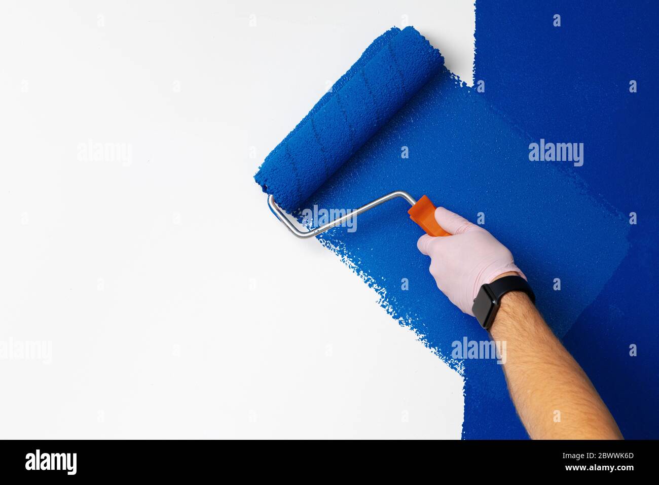 Gloved male hand painting wall into classic blue color Stock Photo - Alamy