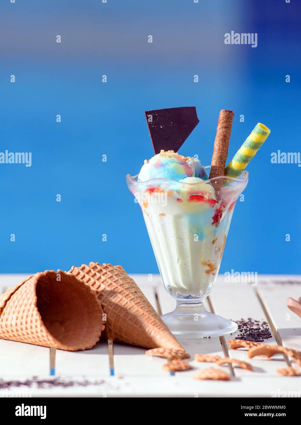 Closeup of glass with rainbow ice cream and colorful syrup on blur ...