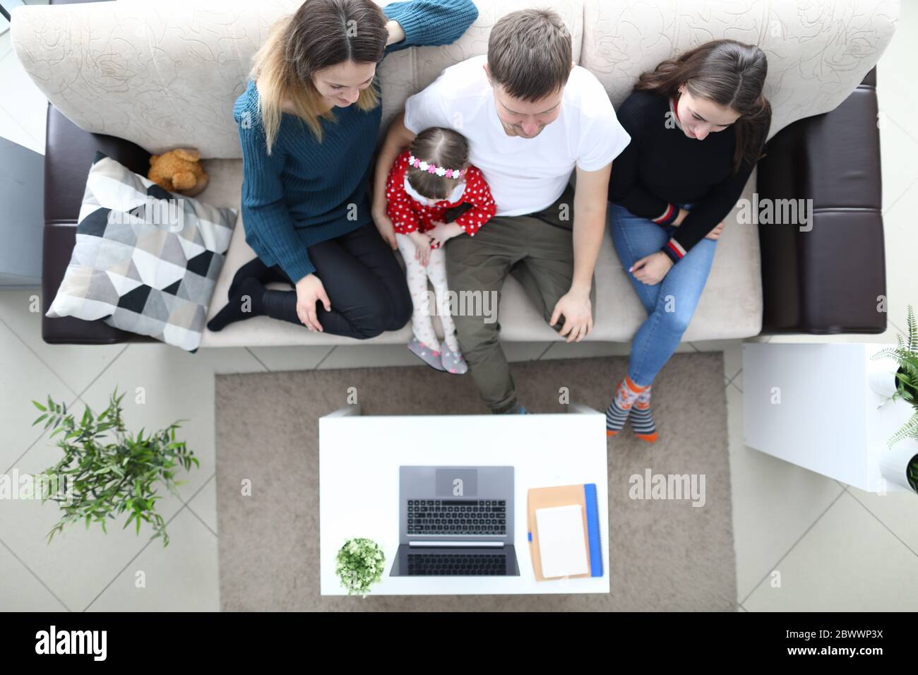 Parents with children sit on sofa in front laptop Stock Photo - Alamy