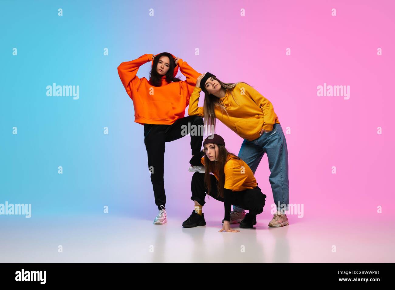 Flexible. Sportive girls dancing hip-hop in stylish clothes on colorful ...
