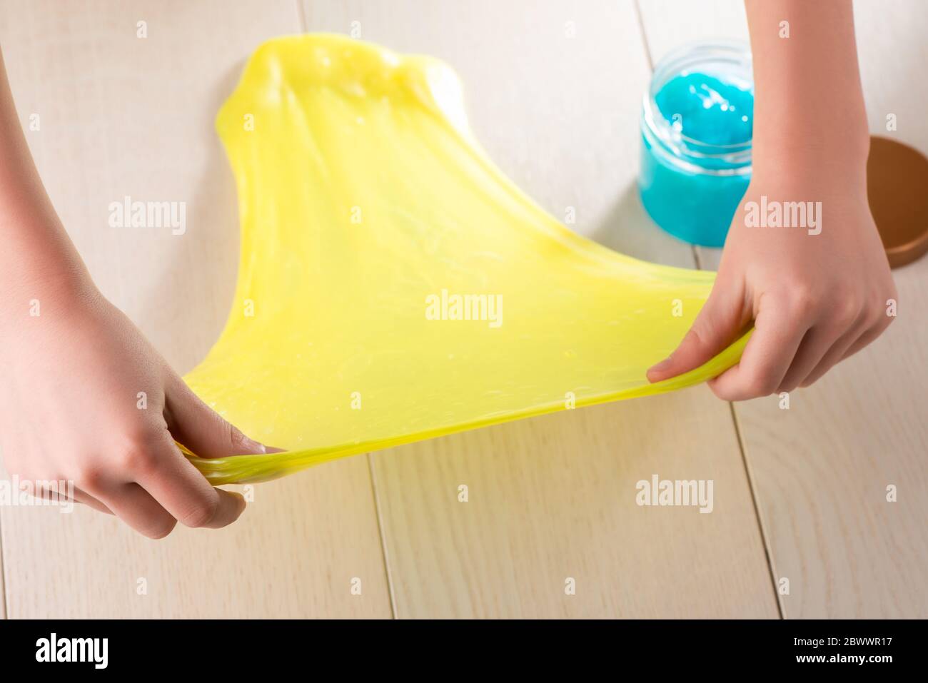 Child playing with yellow and blue slime on wooden table Stock Photo ...