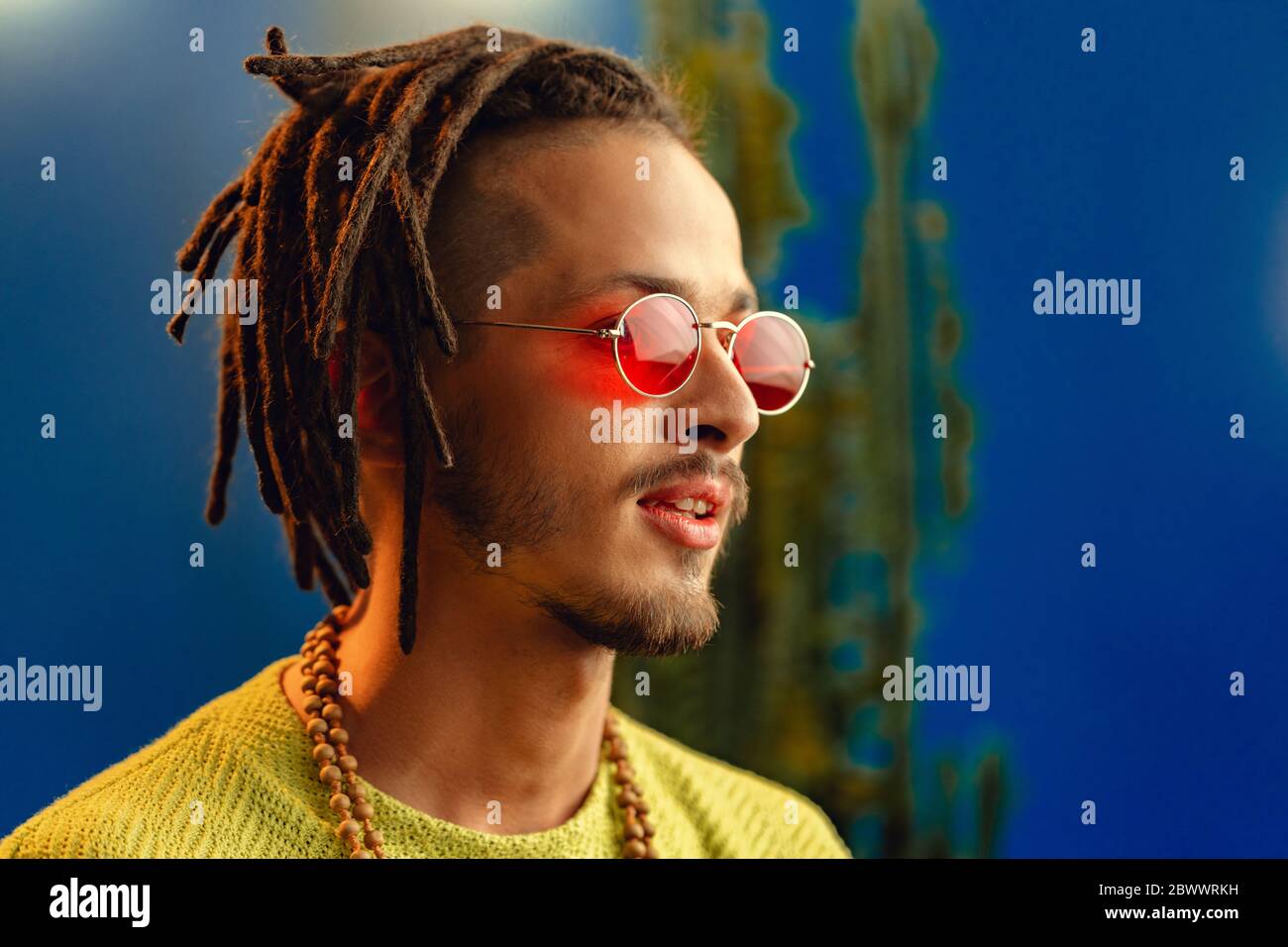 Portrait of a positive handsome caucasian guy with dreadlocks against ...