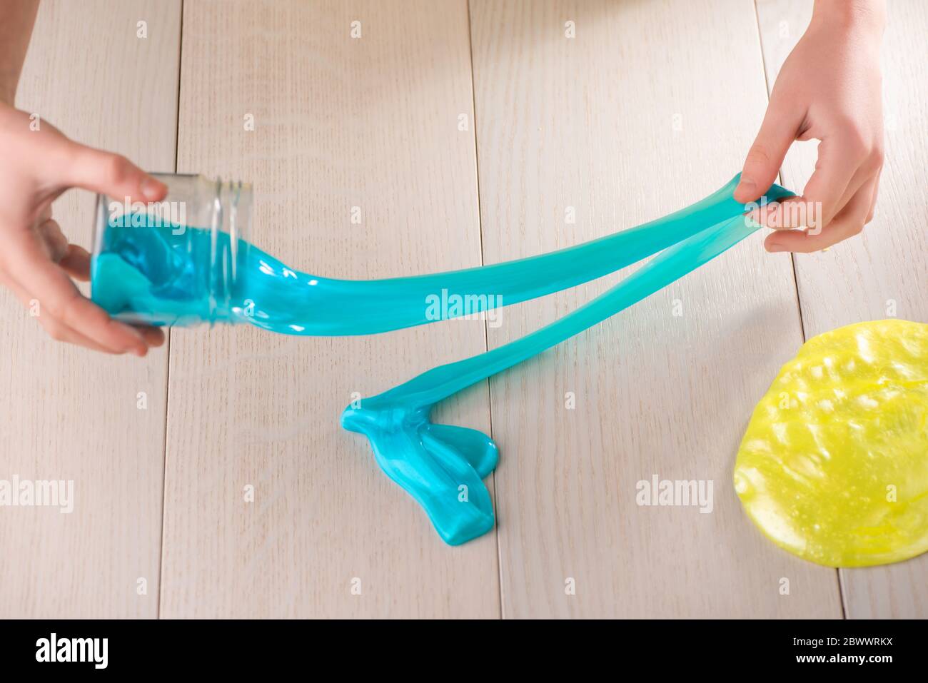 Little girl playing with blue and yellow slimes, top view Stock Photo ...