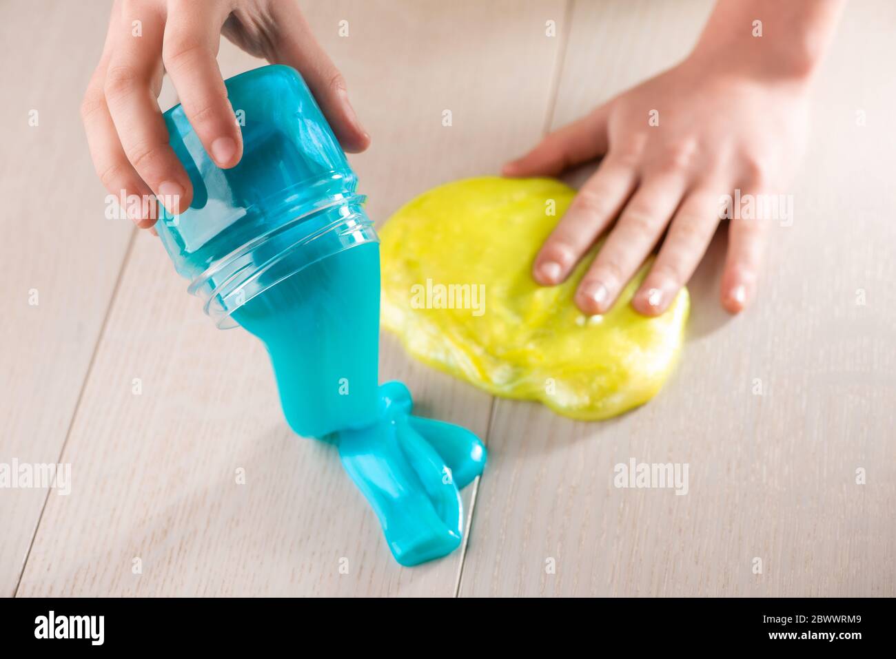 Girl playing with blue and yellow slimes on wooden table Stock Photo ...