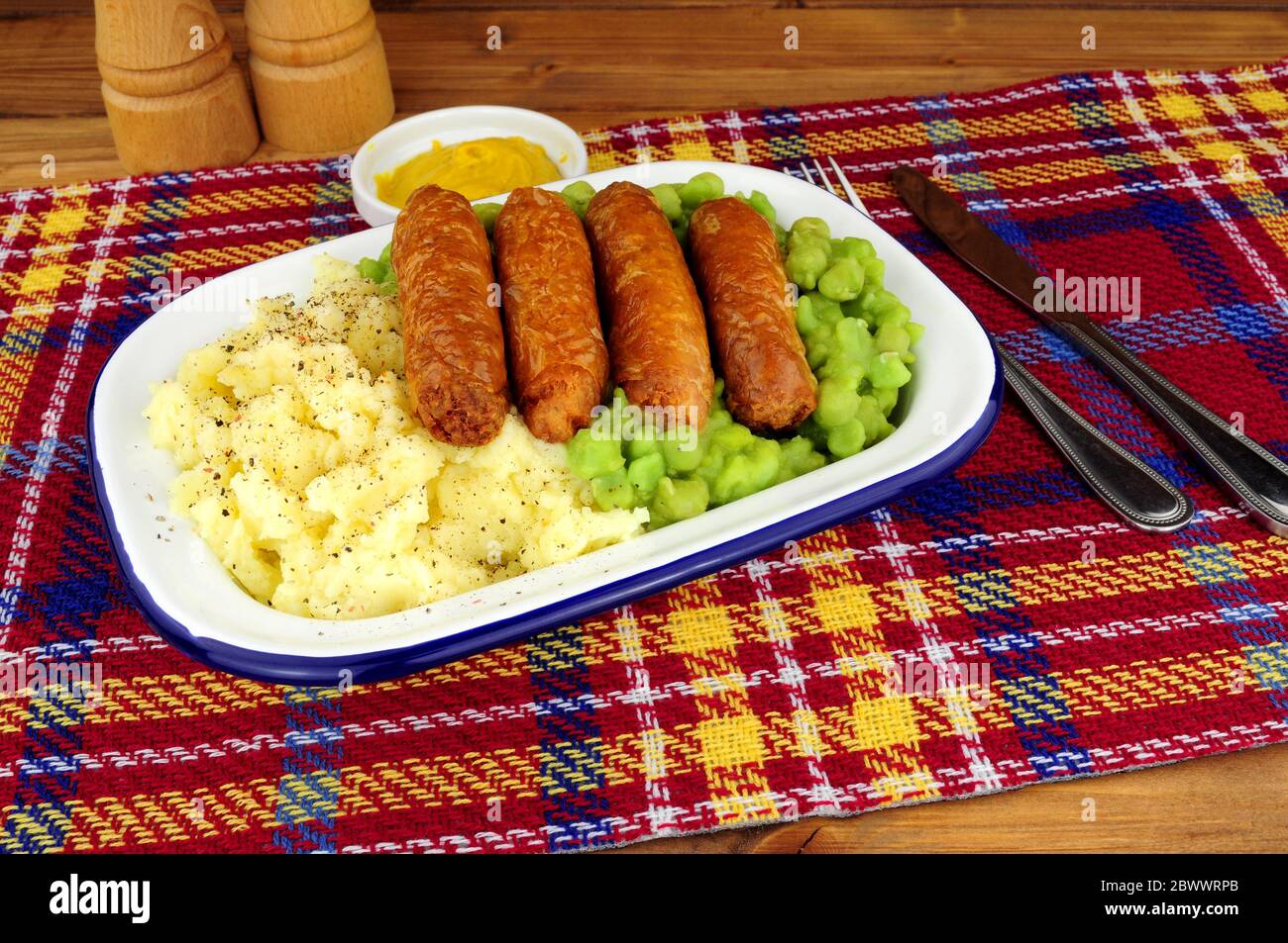 Sausage and mashed potato meal with mushy peas in a metal enamel dish ...