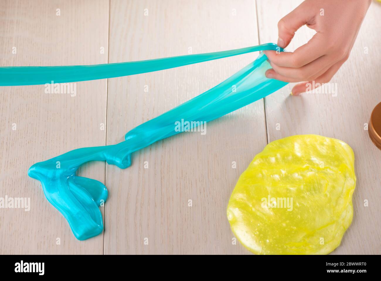 Child playing with blue and yellow slimes, top view Stock Photo - Alamy