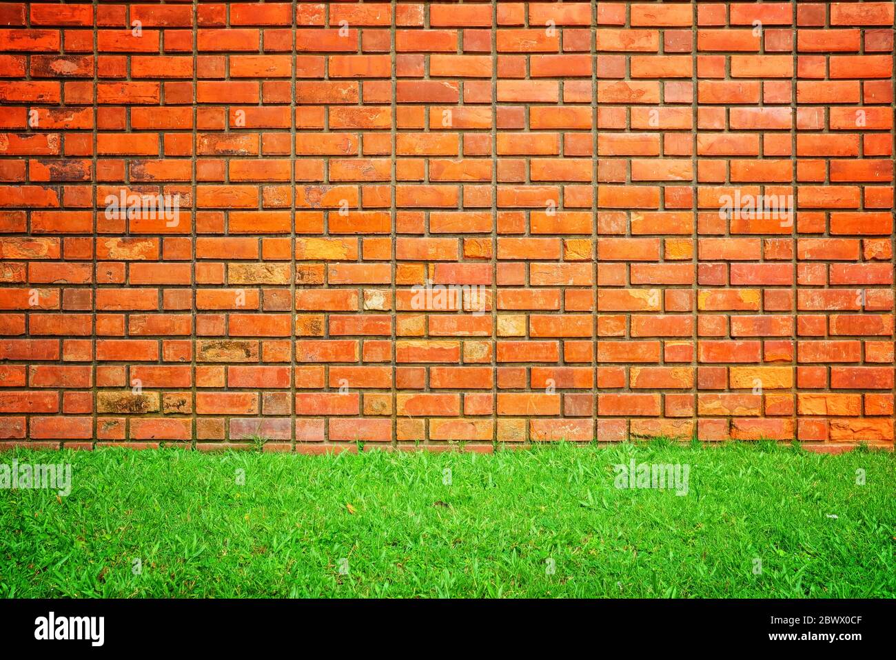 Red Brick wall with Green Field Background Stock Photo - Alamy