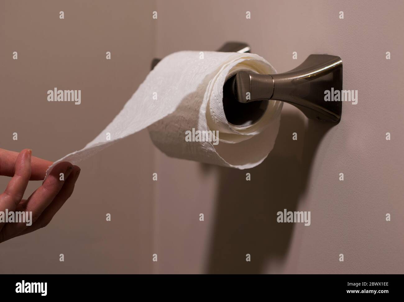 Using toilet paper in bathroom. Close up of hand taking toilet paper ...