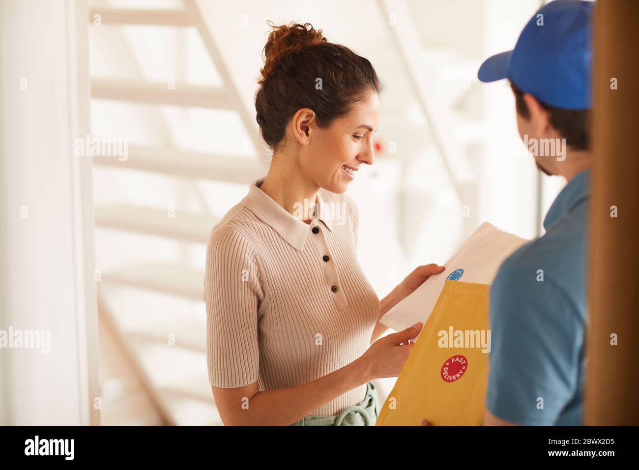 Young woman satisfied the delivery she getting parcels from postman ...