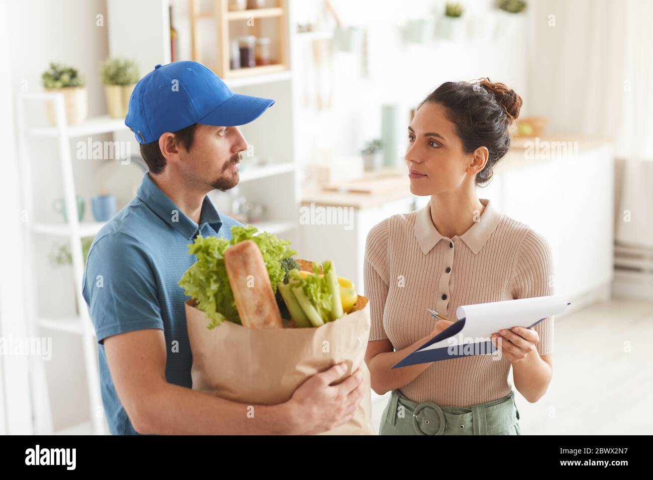 Young woman signing the contract for delivery while delivery man ...
