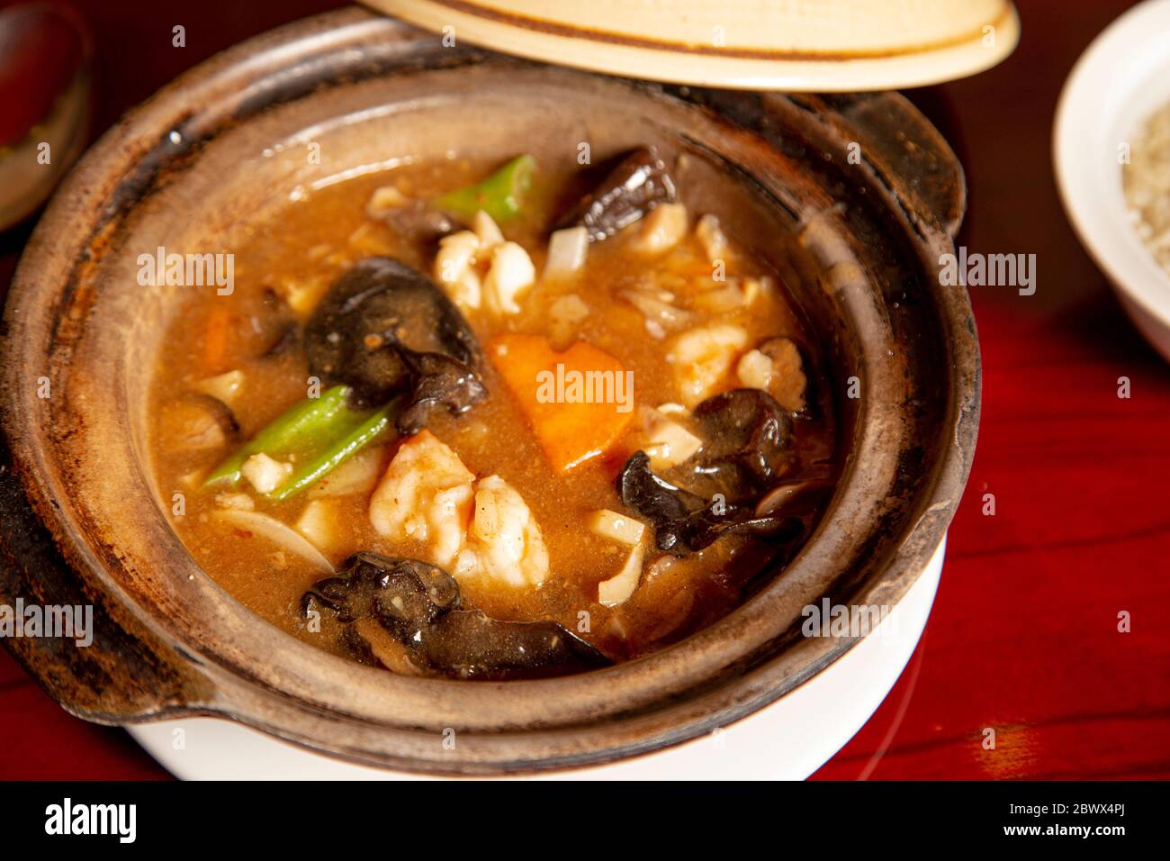 Puffed rice casserole with monkfish and seafood on wooden table ...