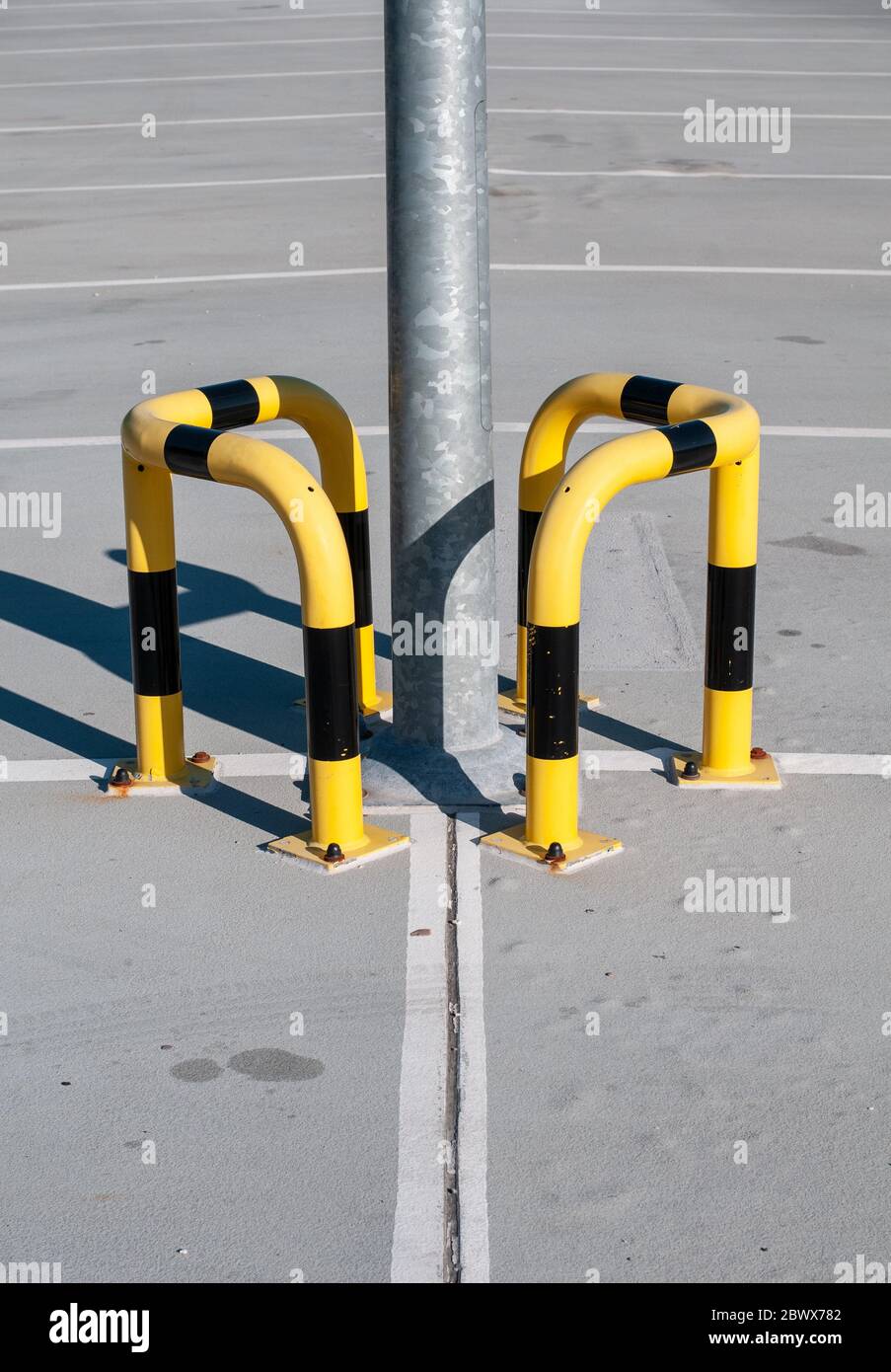 a barrier of black and yellow painted metal protecting a lamppost at a ...