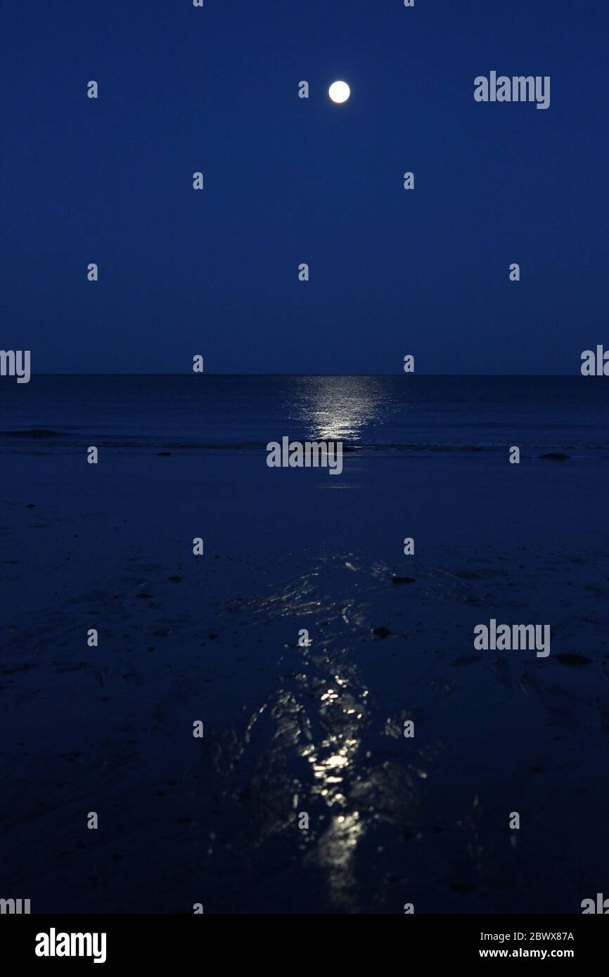 Full Moon setting over sea at Tywyn, Mid Wales Stock Photo - Alamy