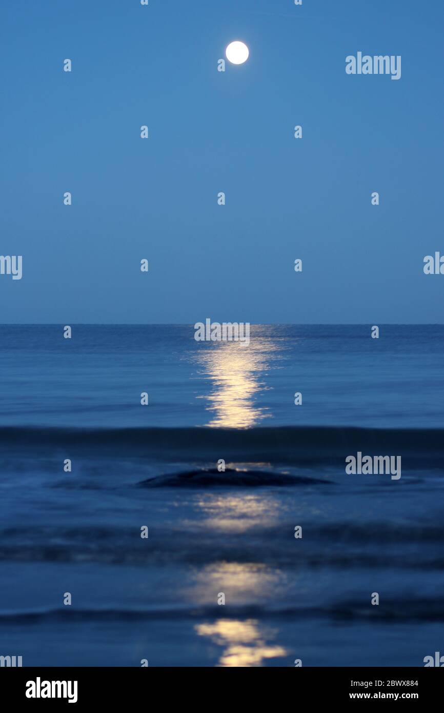 Full Moon setting over sea at Tywyn, Mid Wales Stock Photo - Alamy