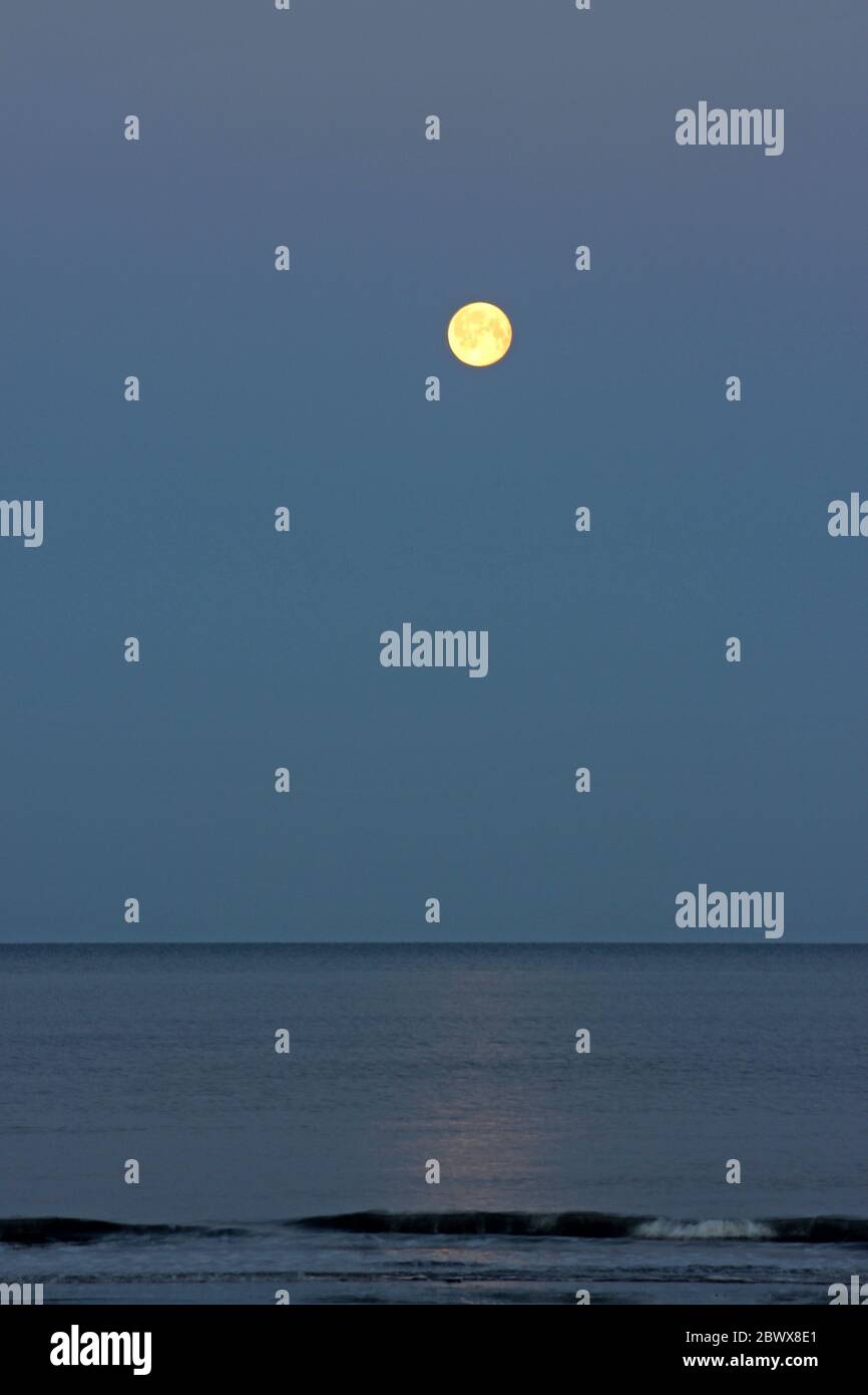 Full Moon setting over sea at Tywyn, Mid Wales Stock Photo - Alamy