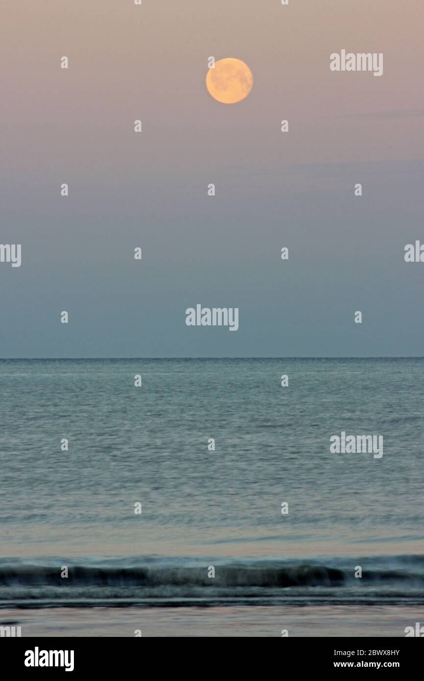 Full Moon setting over sea at Tywyn, Mid Wales Stock Photo - Alamy
