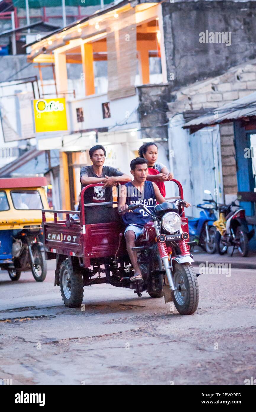 Local filipino workers ride through Coron on their motorbike driven ...