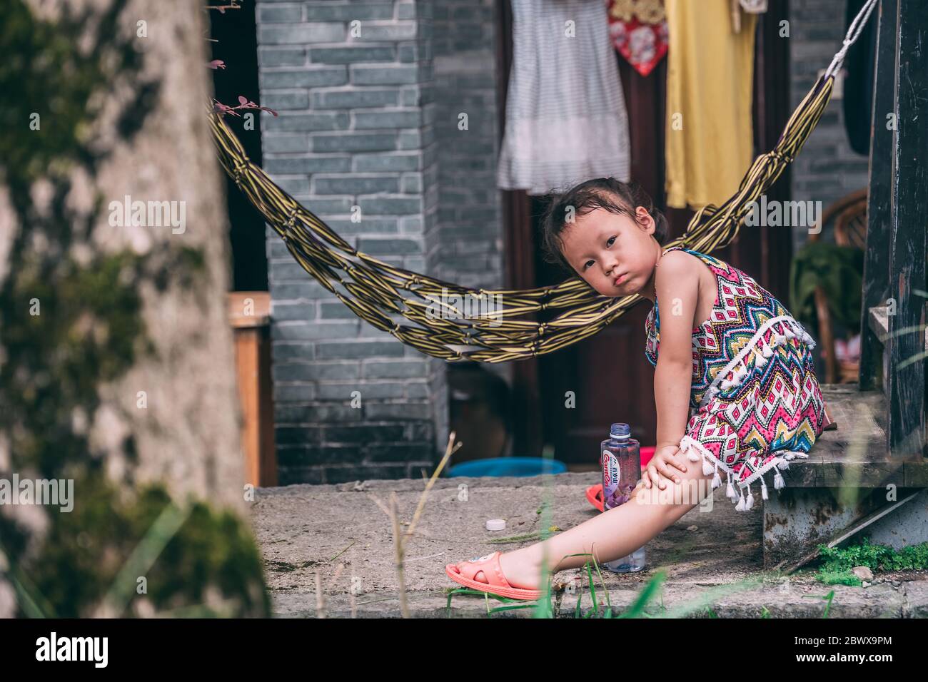 Yangshuo, China - August 2019 : Cute little chinese girl sitting on the ...