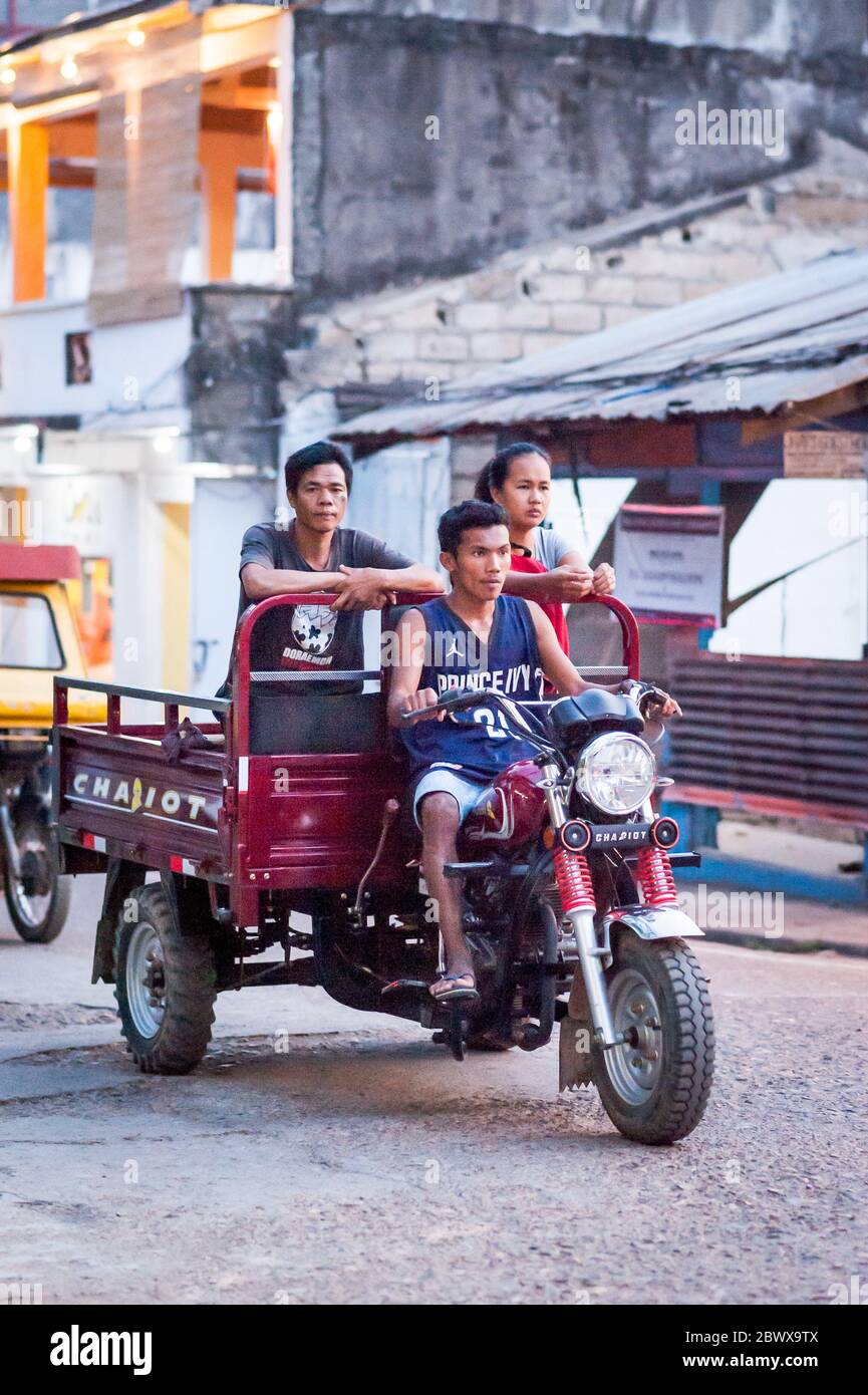 Local filipino workers ride through Coron on their motorbike driven ...