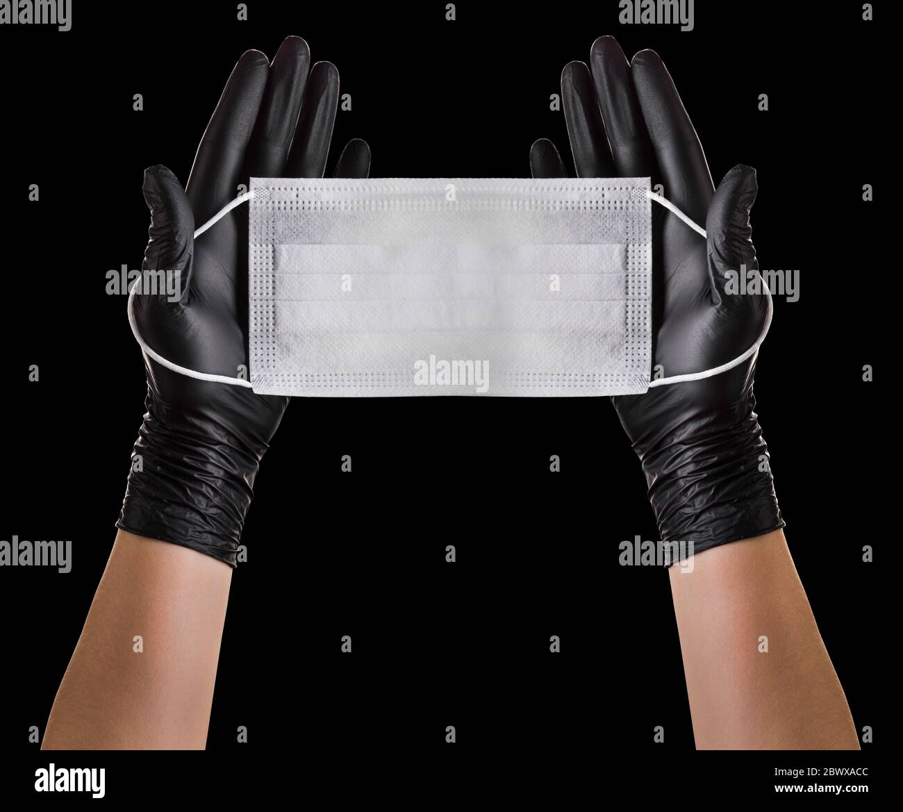 Hand in black gloves wearing disposable face mask isolated on black ...