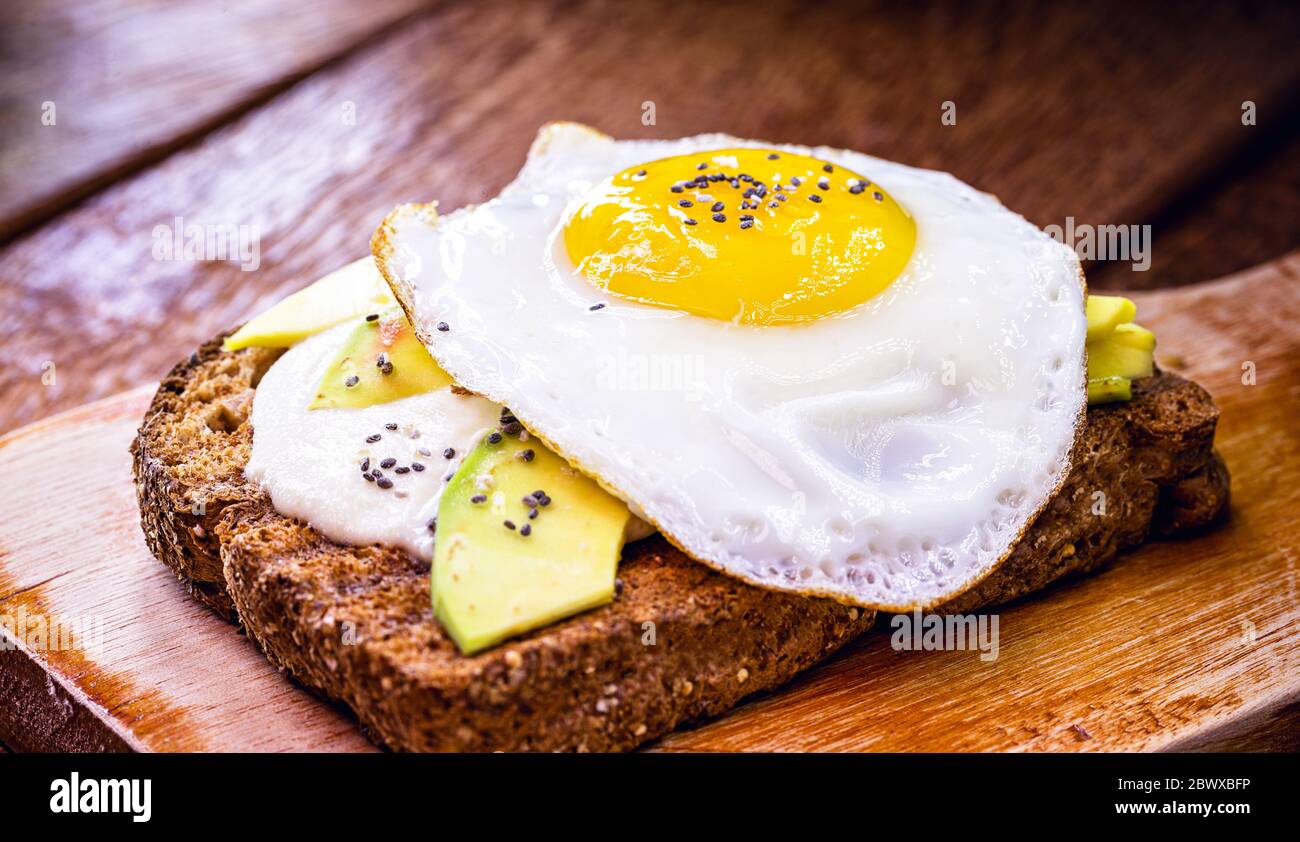 Tasty avocado sliced on crunchy rye toast, with cream, fried egg ...