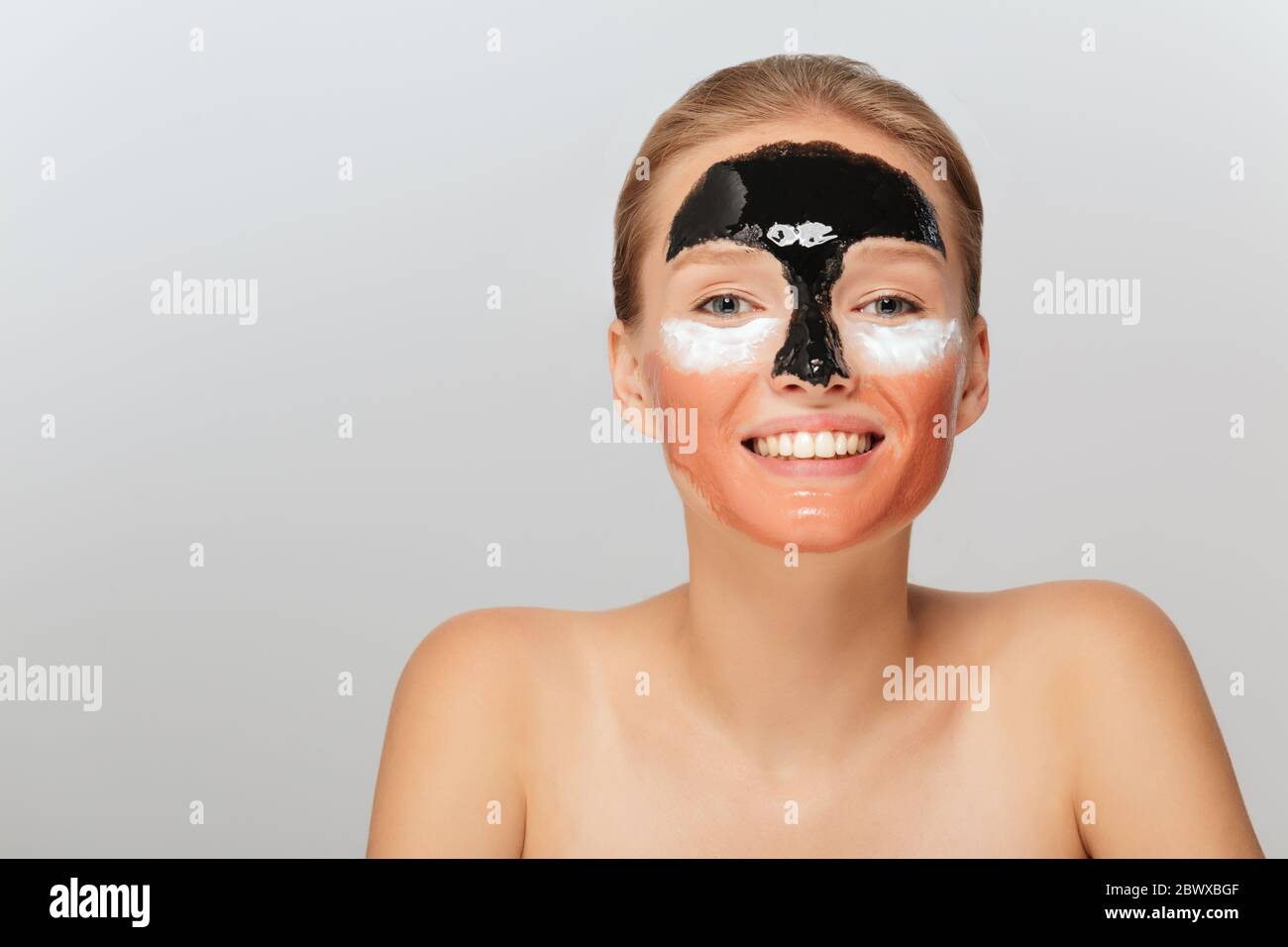 Portrait of young smiling woman with different cosmetic masks on face ...