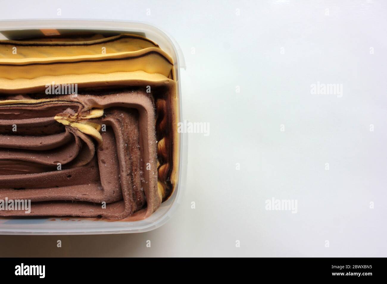 Orange and chocolate ice cream in a plastic box on white background ...
