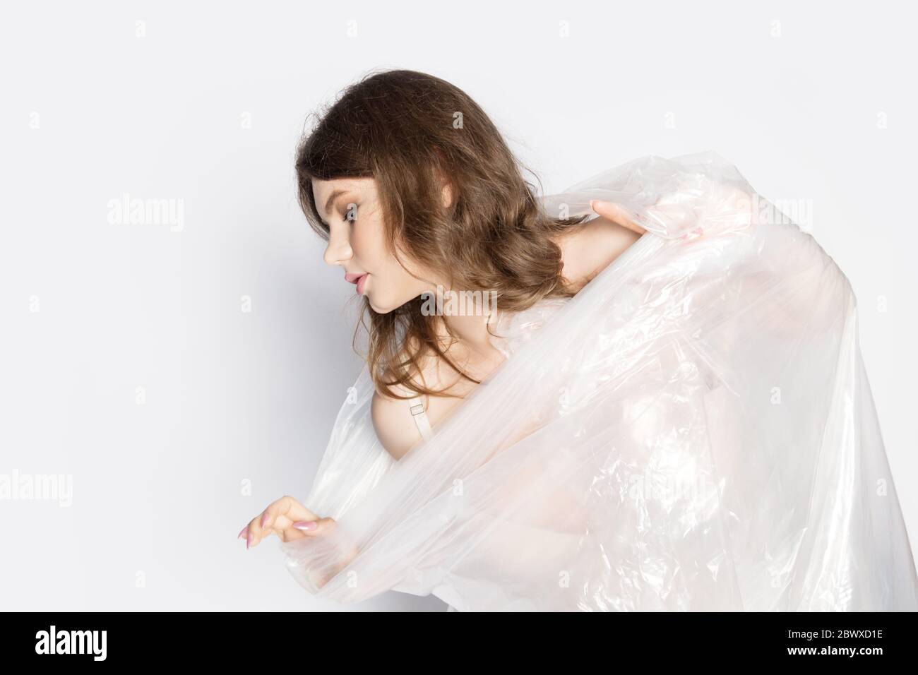 Young beautiful woman in plastic in the studio. Ecology and plastic ...