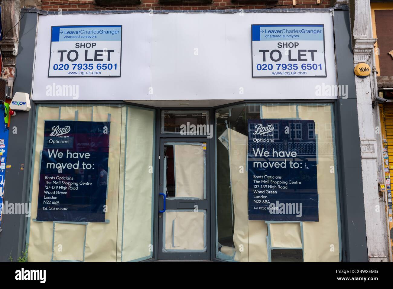 Two shop to let sign above a vacant retail shop with covered windows ...