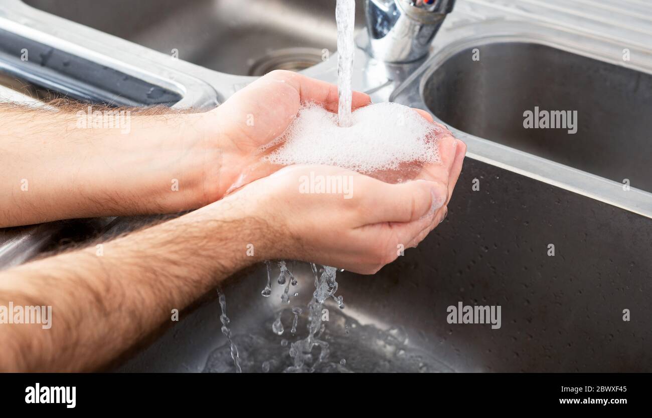 Man washes hands in metal sink using soap. Caucasian man wash hands ...
