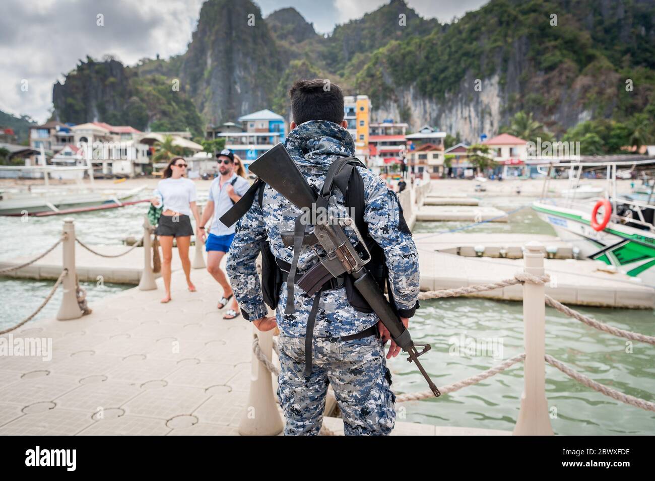 An armed Filipino coast guard watches tourists board day boats heading ...