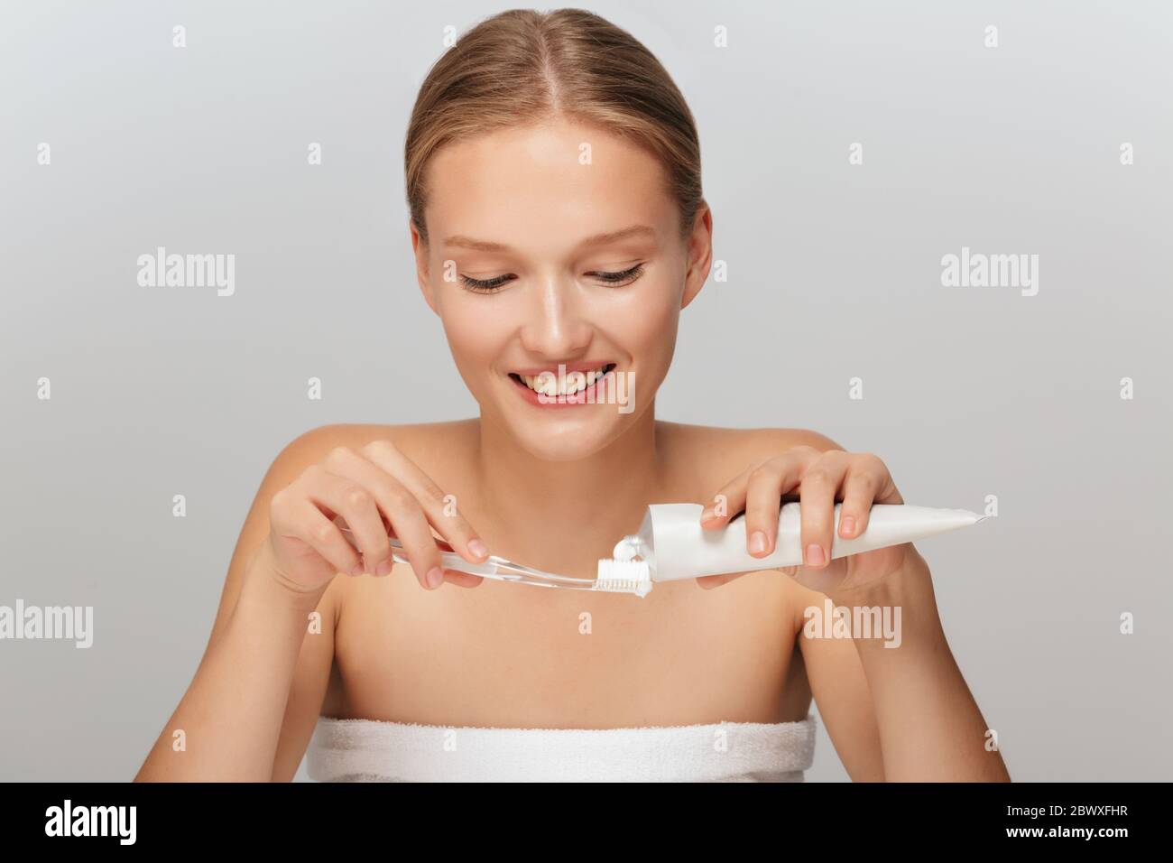 Portrait of young cheerful woman without makeup happily putting some ...