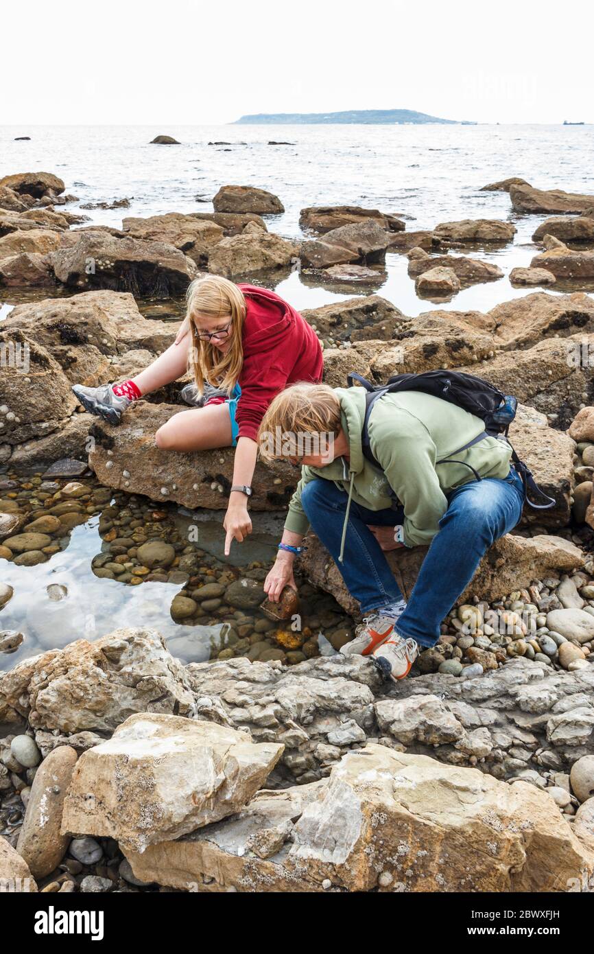 A fourteen year-old girl and her mother exploring rock pools on the ...