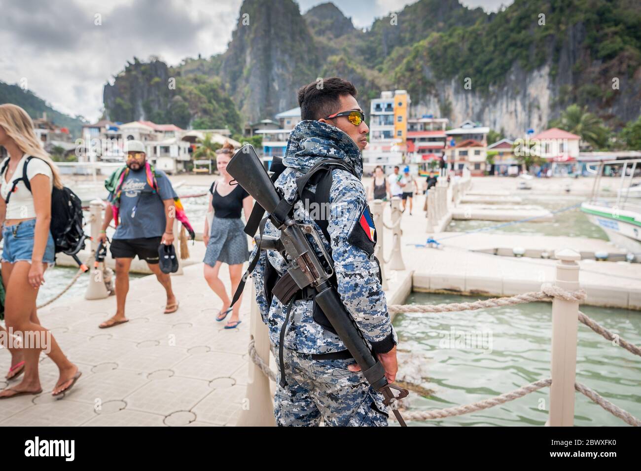 An armed Filipino coast guard watches tourists board day boats heading ...