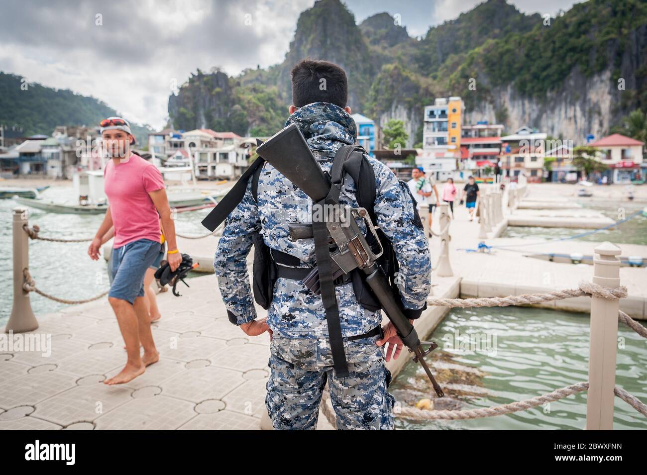 An armed Filipino coast guard watches tourists board day boats heading ...