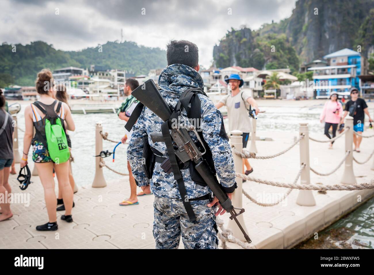 An armed Filipino coast guard watches tourists board day boats heading ...