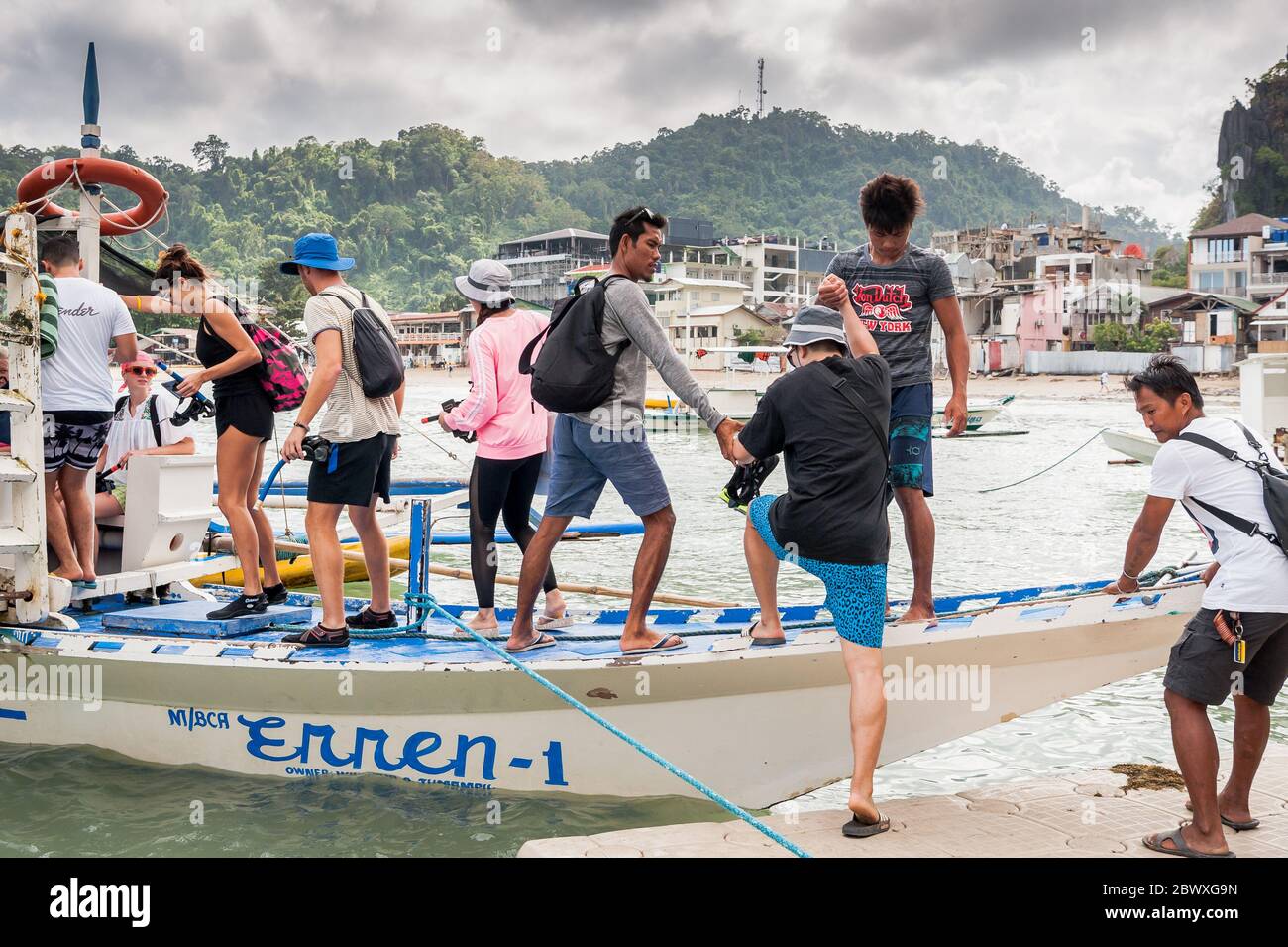Tourists board a traditional Asian long tail boat early in the morning ...