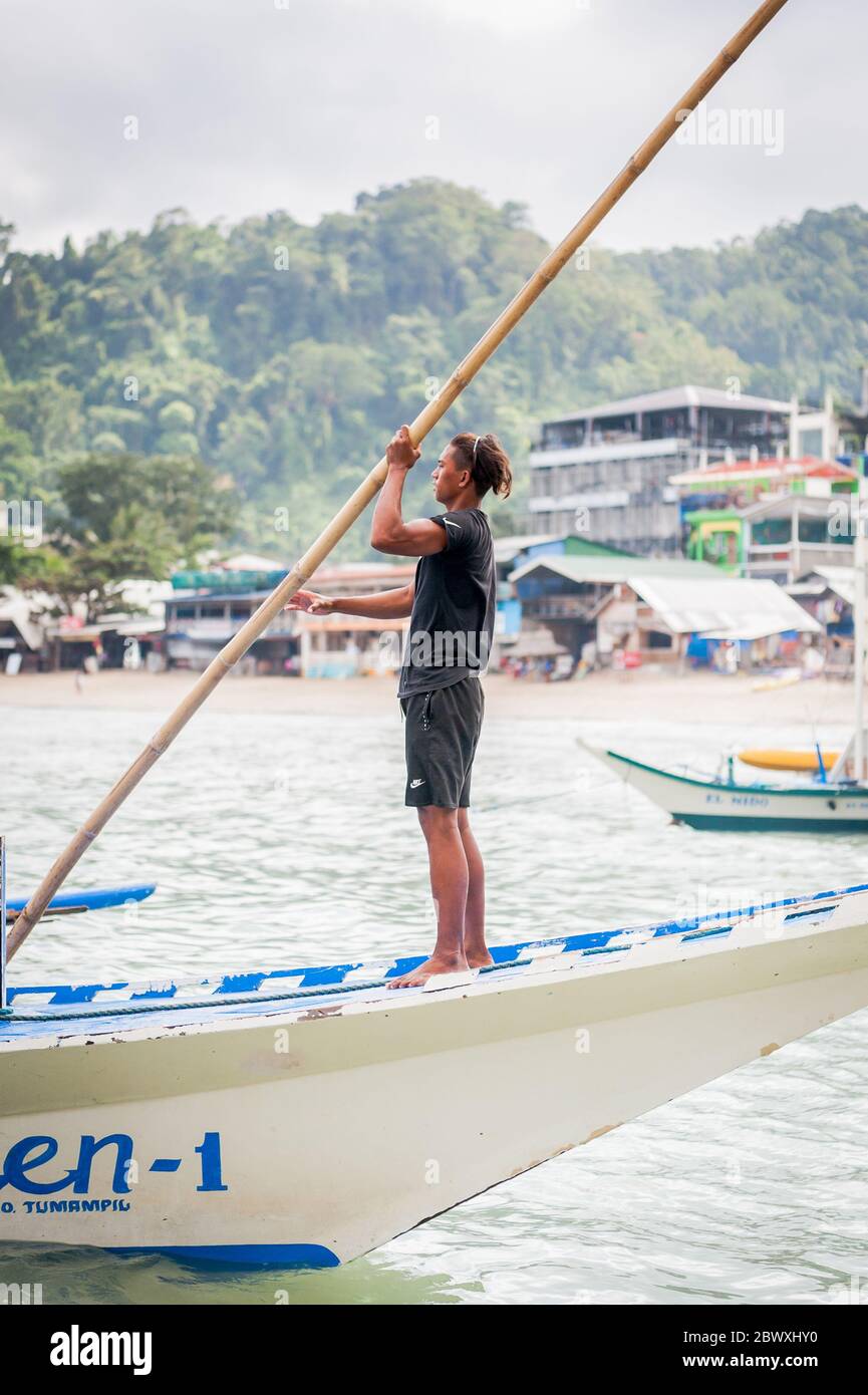 A Filipino boat captain steers his boat full of tourists out of harbour ...