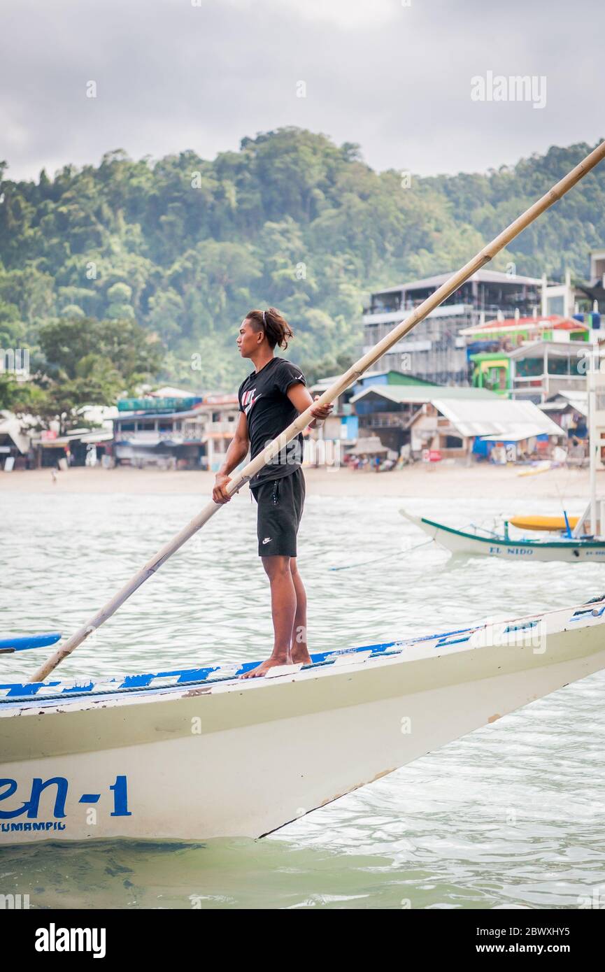 A Filipino boat captain steers his boat full of tourists out of harbour ...