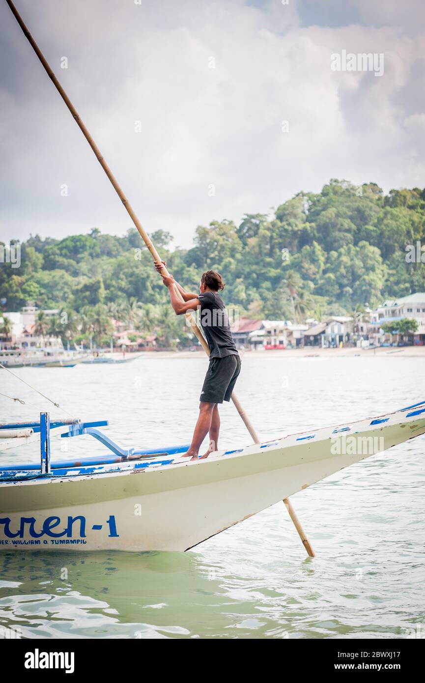 A Filipino boat captain steers his boat full of tourists out of harbour ...
